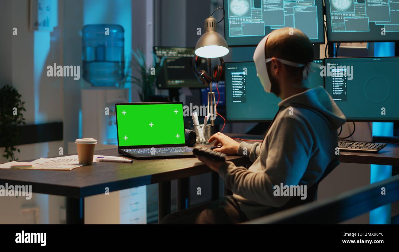 Impostor with mask hacking network with greenscreen on laptop, breaking ...