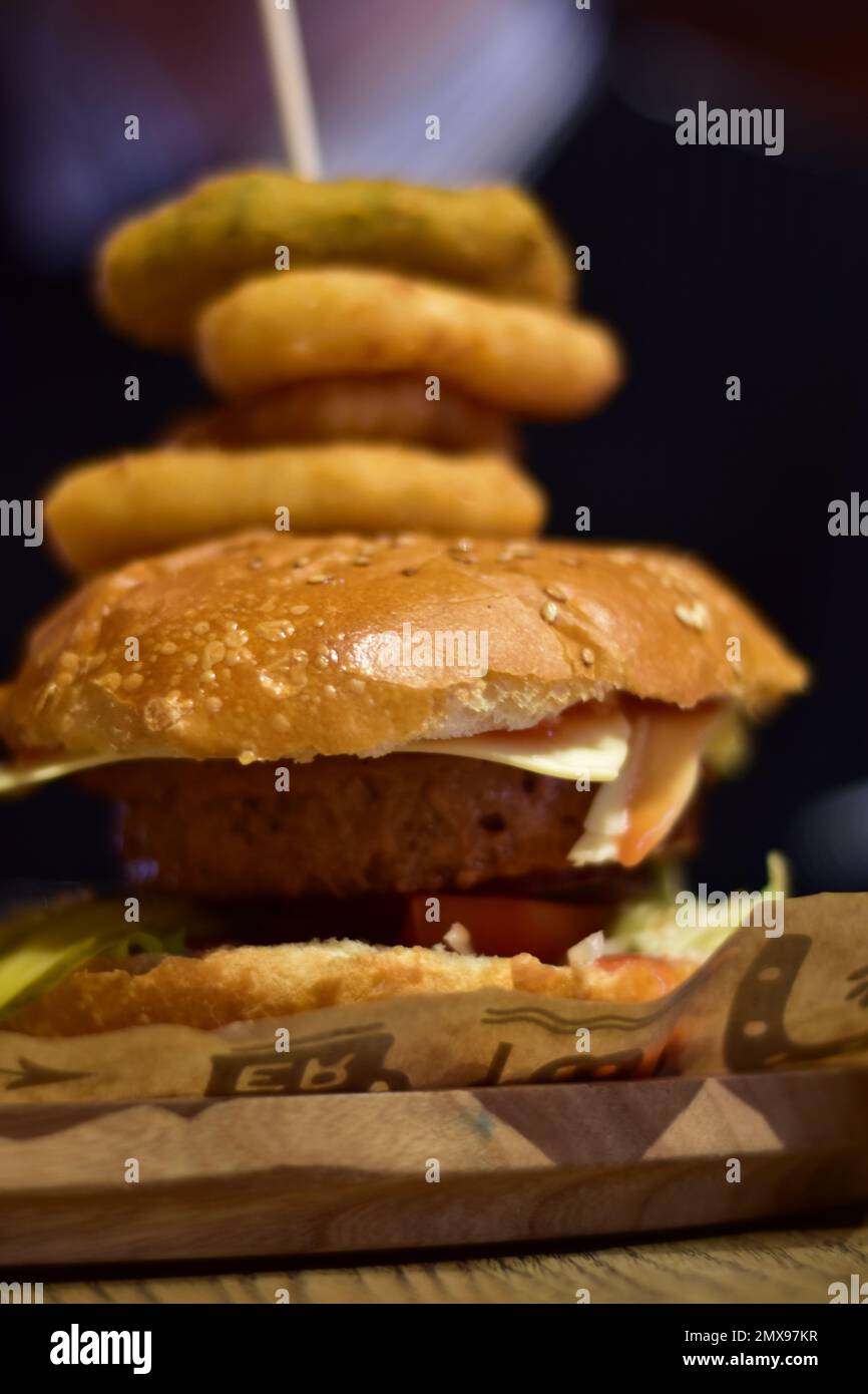 Vegan burger in a restaurant with onion rings on top and french fries ...