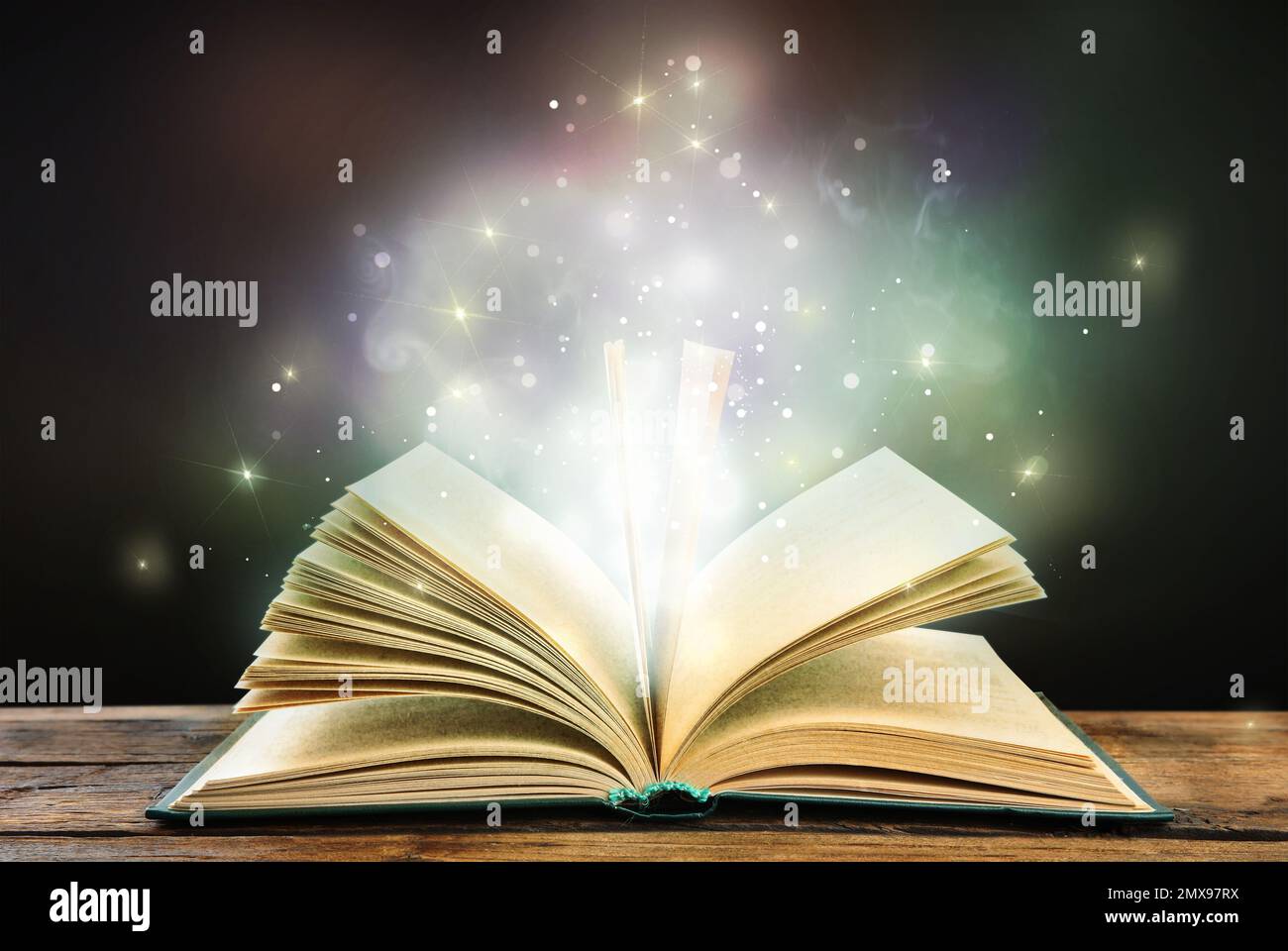 Magic light emanating from open old book on table Stock Photo - Alamy
