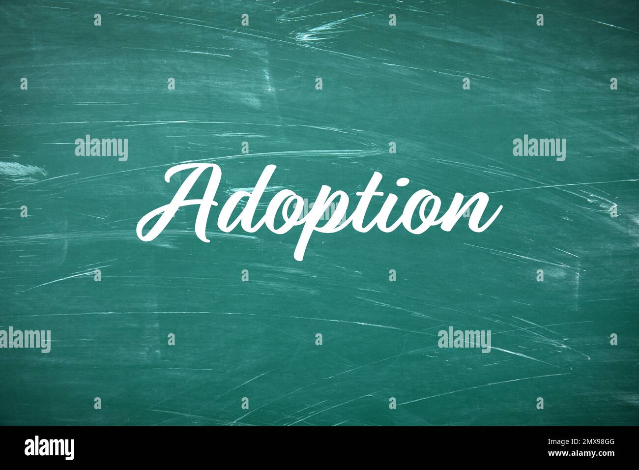 Word ADOPT written with chalk on greenboard, top view. Family concept ...