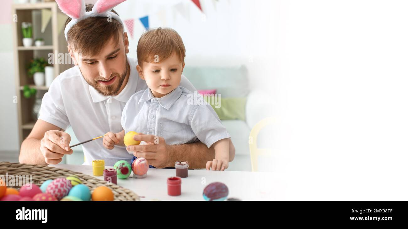 Father painting Easter eggs with his child at home. Banner for design ...