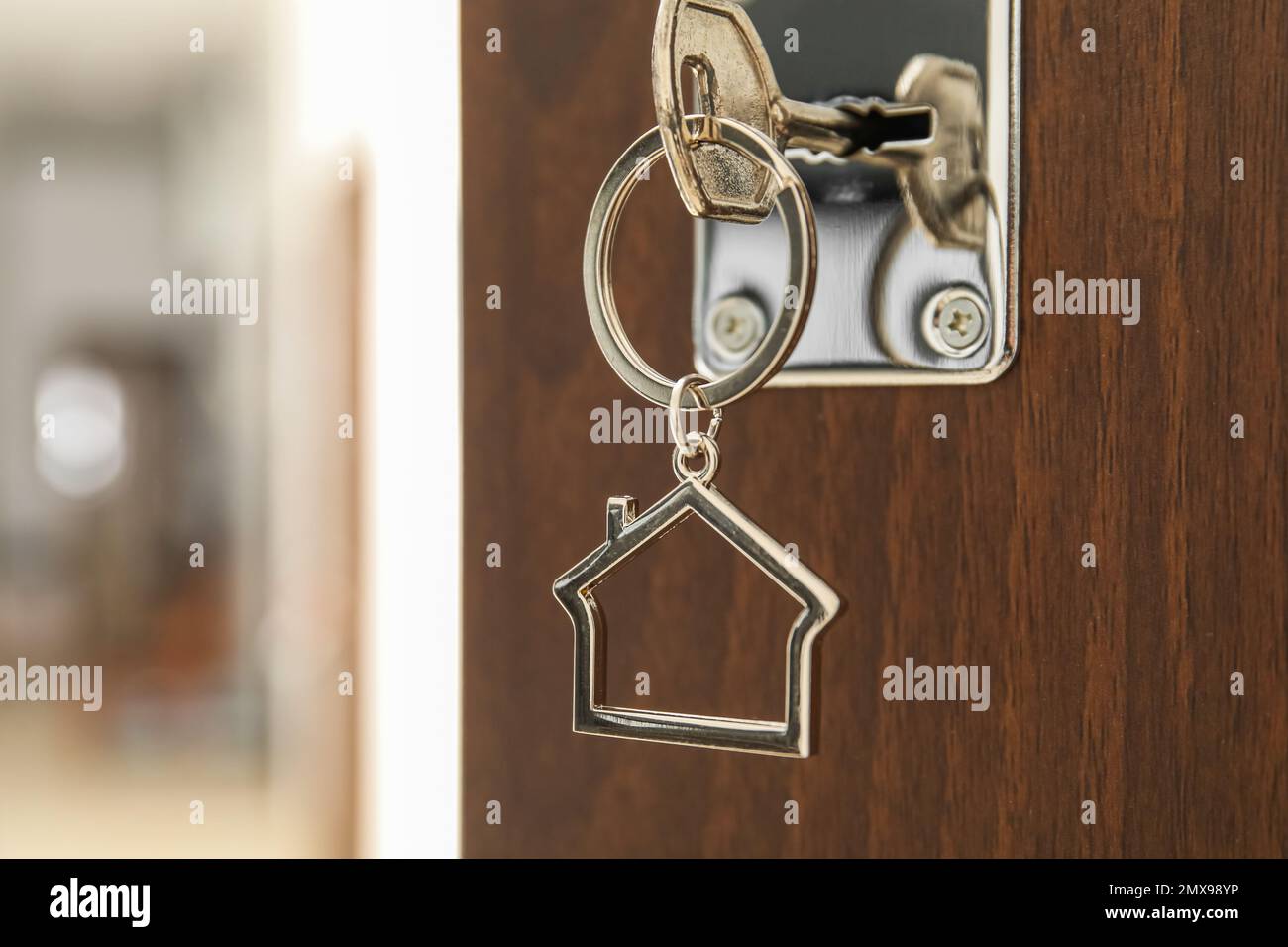Key with stylish keychain in door lock, closeup Stock Photo - Alamy