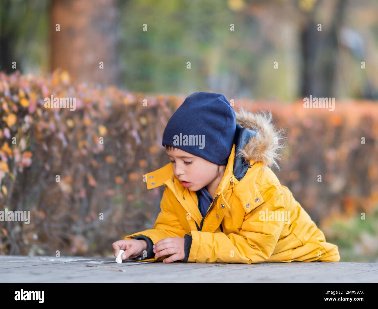 Little boy writes or draws something with chalk on pavement. Creative ...