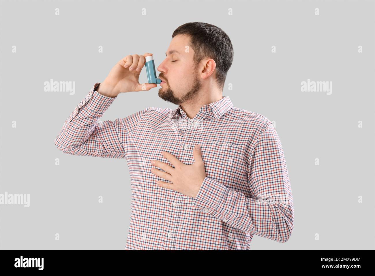 Sick man with inhaler on light background Stock Photo - Alamy