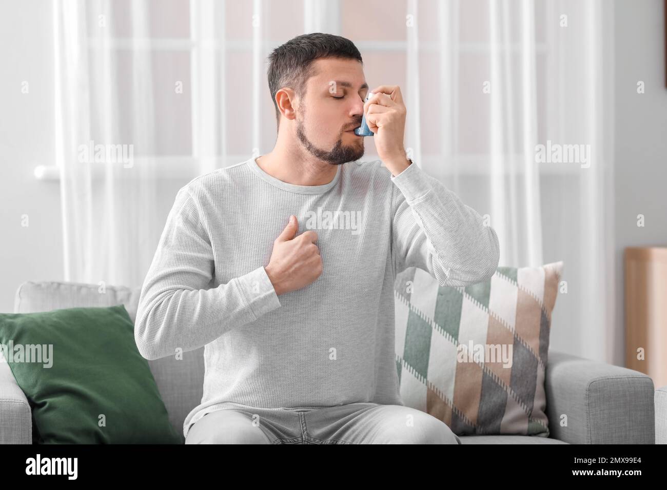 Sick man using inhaler at home Stock Photo - Alamy