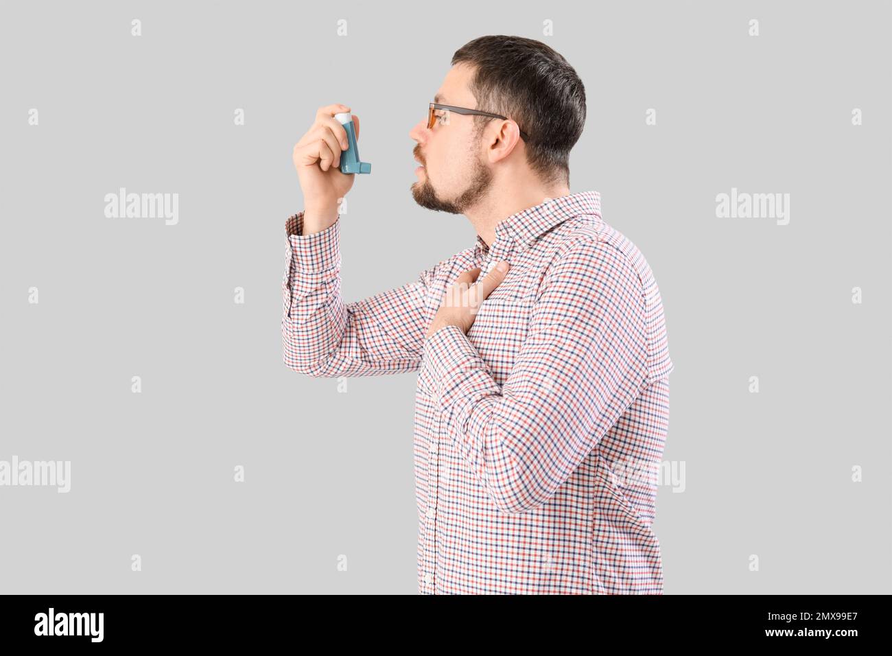 Sick man with inhaler on light background Stock Photo - Alamy