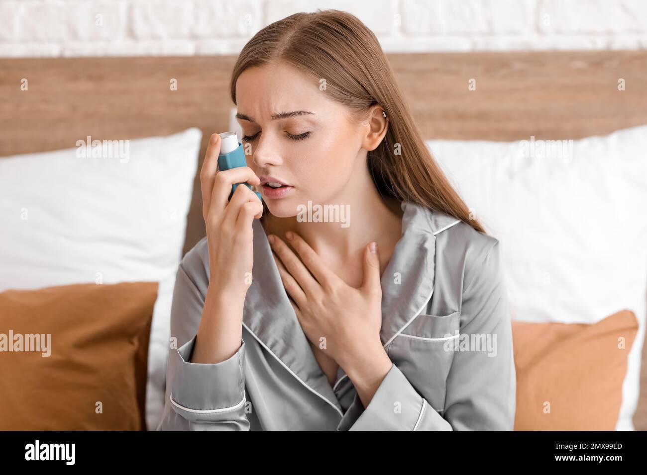 Sick young woman with inhaler in bed Stock Photo - Alamy