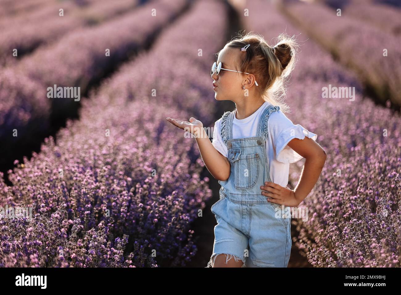 Adorable happy child girl is having fun and blows air kiss at camera in ...