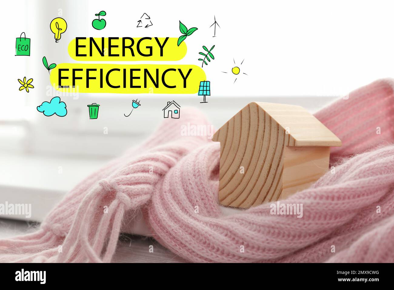 Energy efficiency concept. Wooden house model wrapped in scarf indoors ...