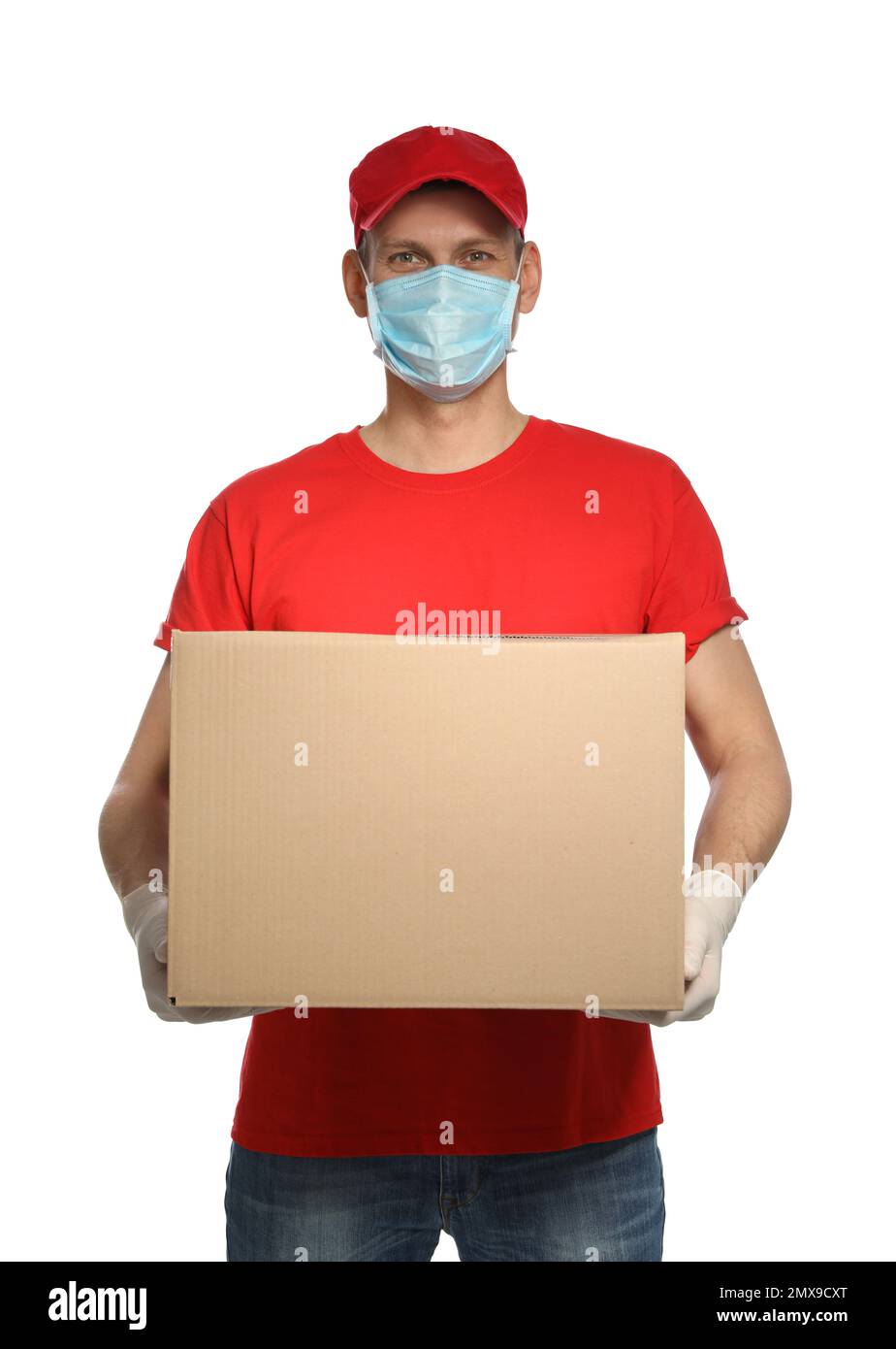 Courier in protective mask and gloves holding cardboard box on white ...