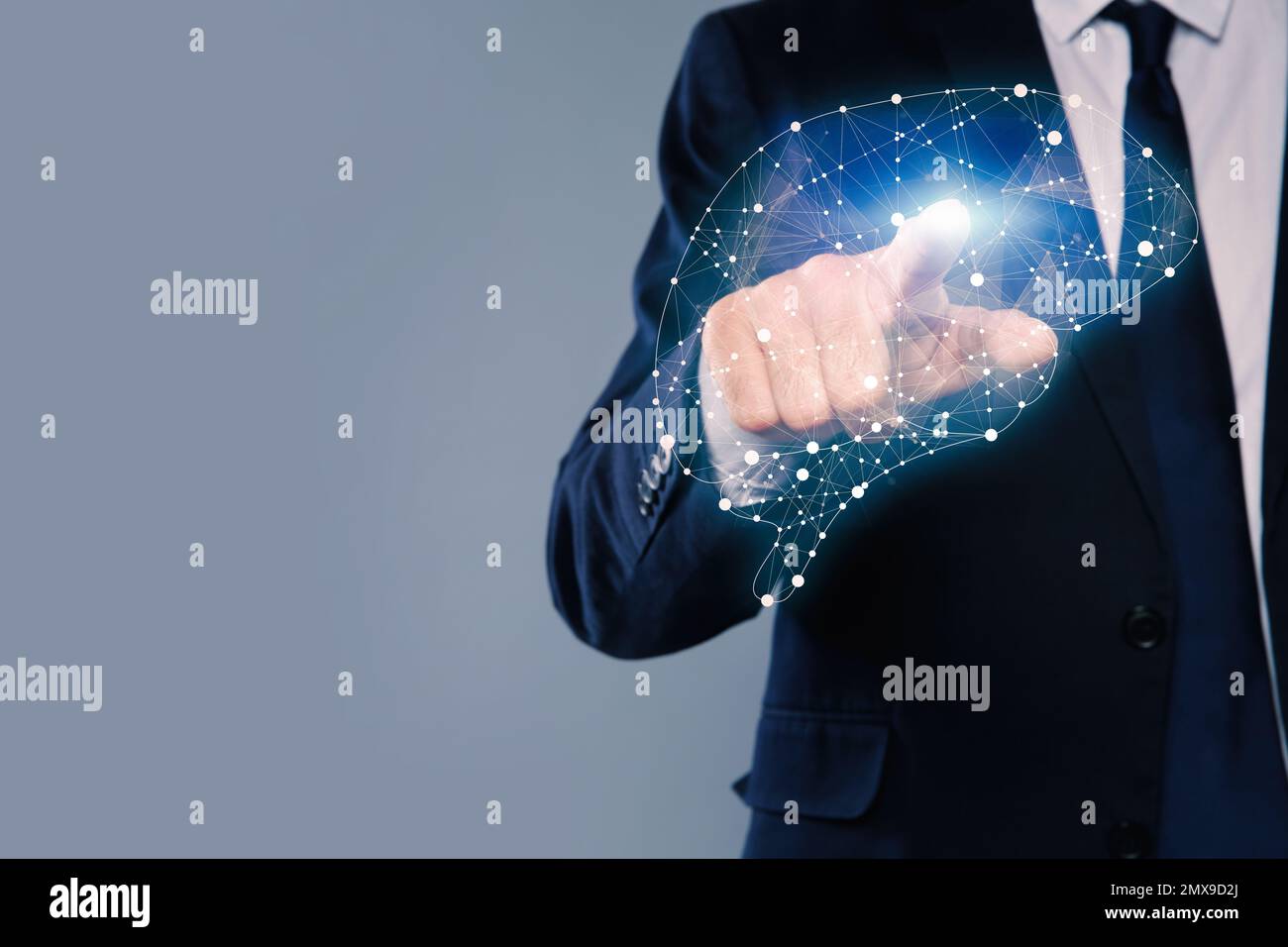 Young man pointing at digital image of brain on grey background ...