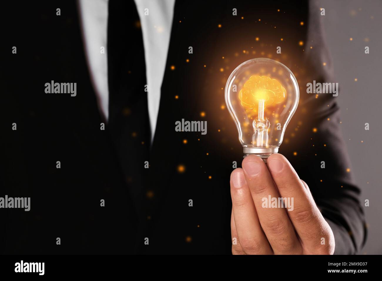 Man holding light bulb with shining brain inside against grey ...