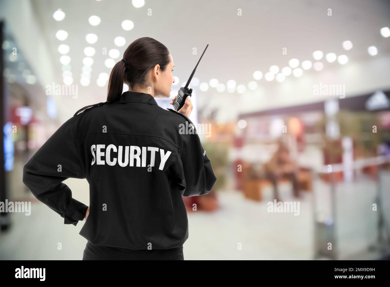 Security guard using portable radio transmitter in shopping mall, space ...