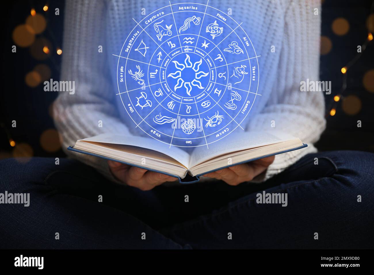 Young woman reading book at home and illustration of zodiac wheel with ...