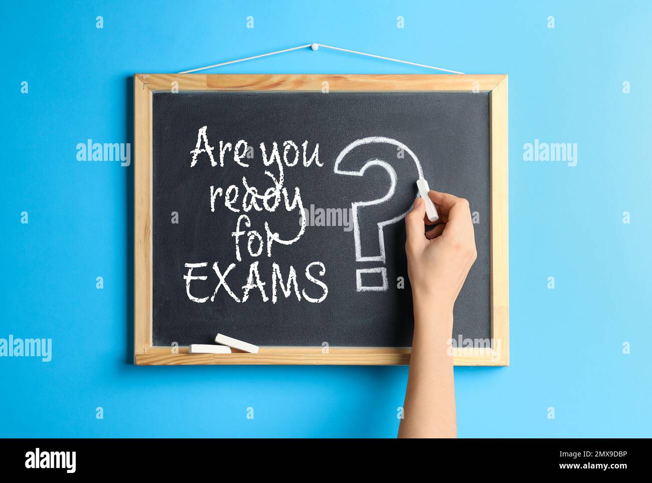 Woman writing phrase ARE YOU READY FOR EXAMS with chalk on blackboard ...