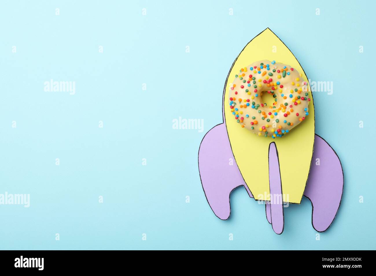 Rocket made with donut and paper on light blue background, top view ...