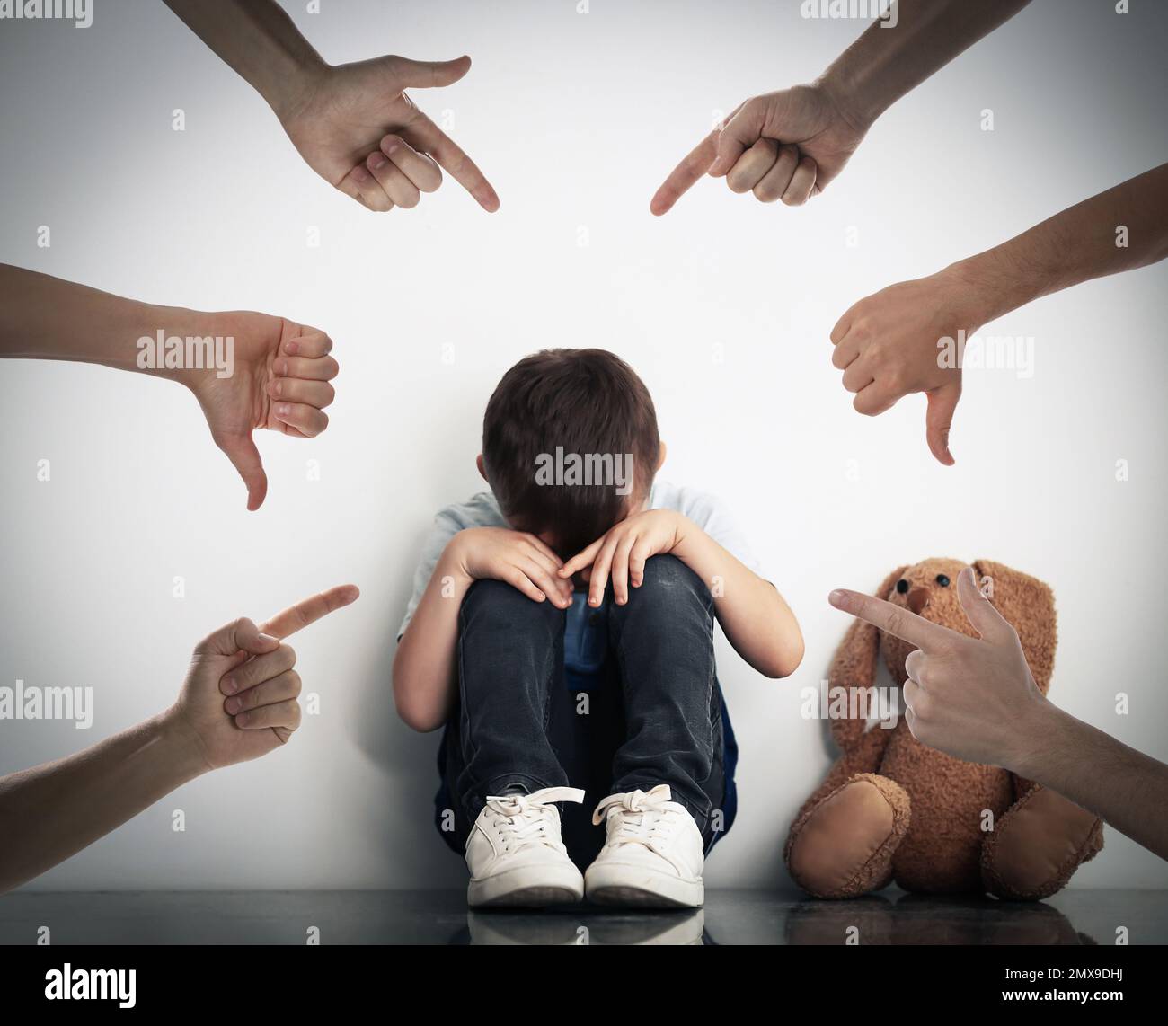 People bullying sad little boy near white wall Stock Photo - Alamy