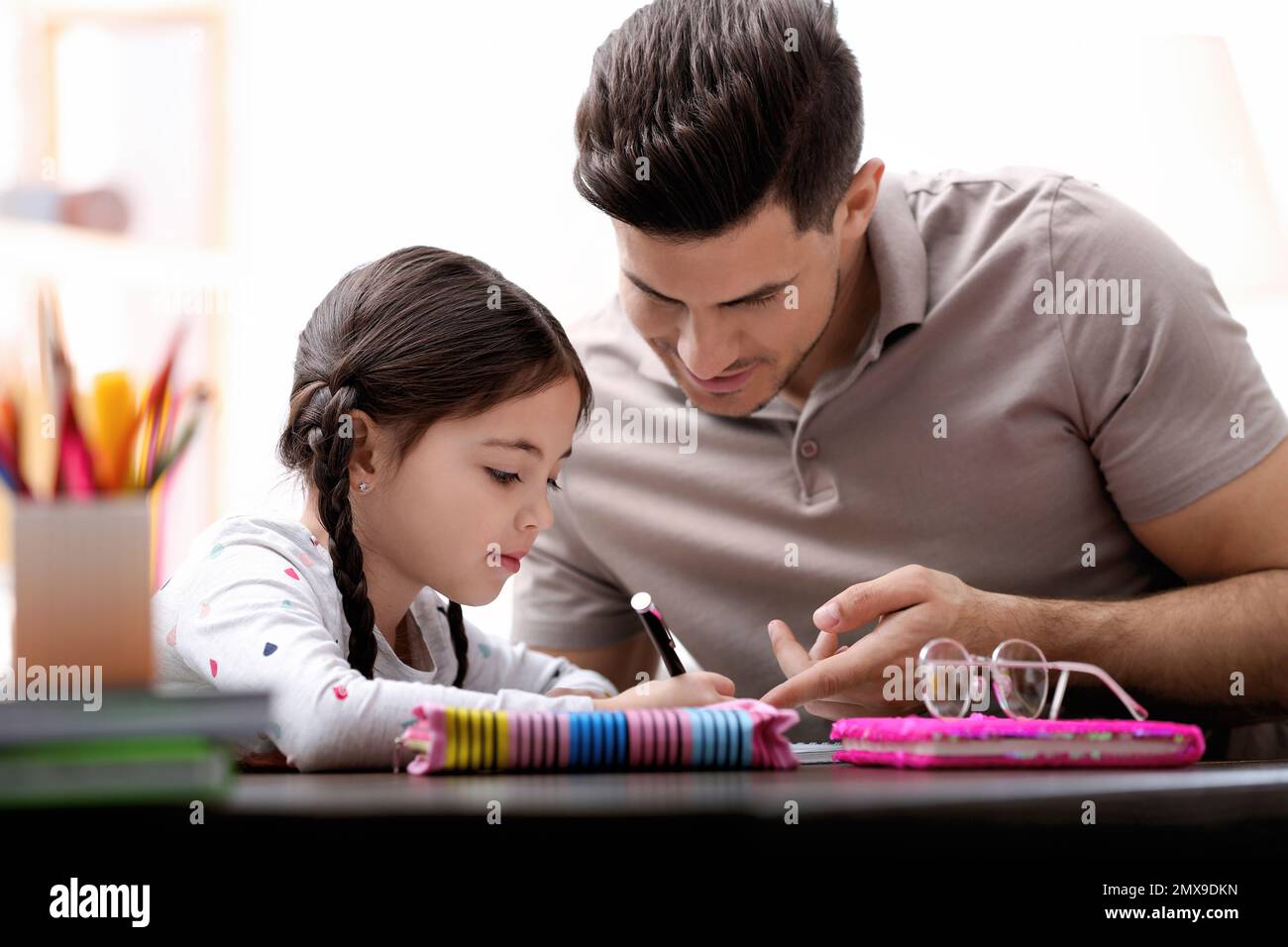 Man helping his daughter with homework at table indoors Stock Photo - Alamy