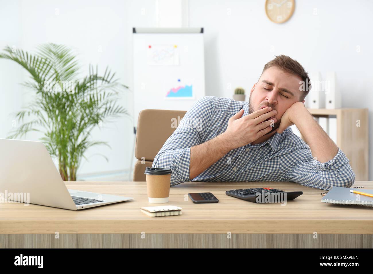 Lazy young office employee yawning at workplace Stock Photo - Alamy