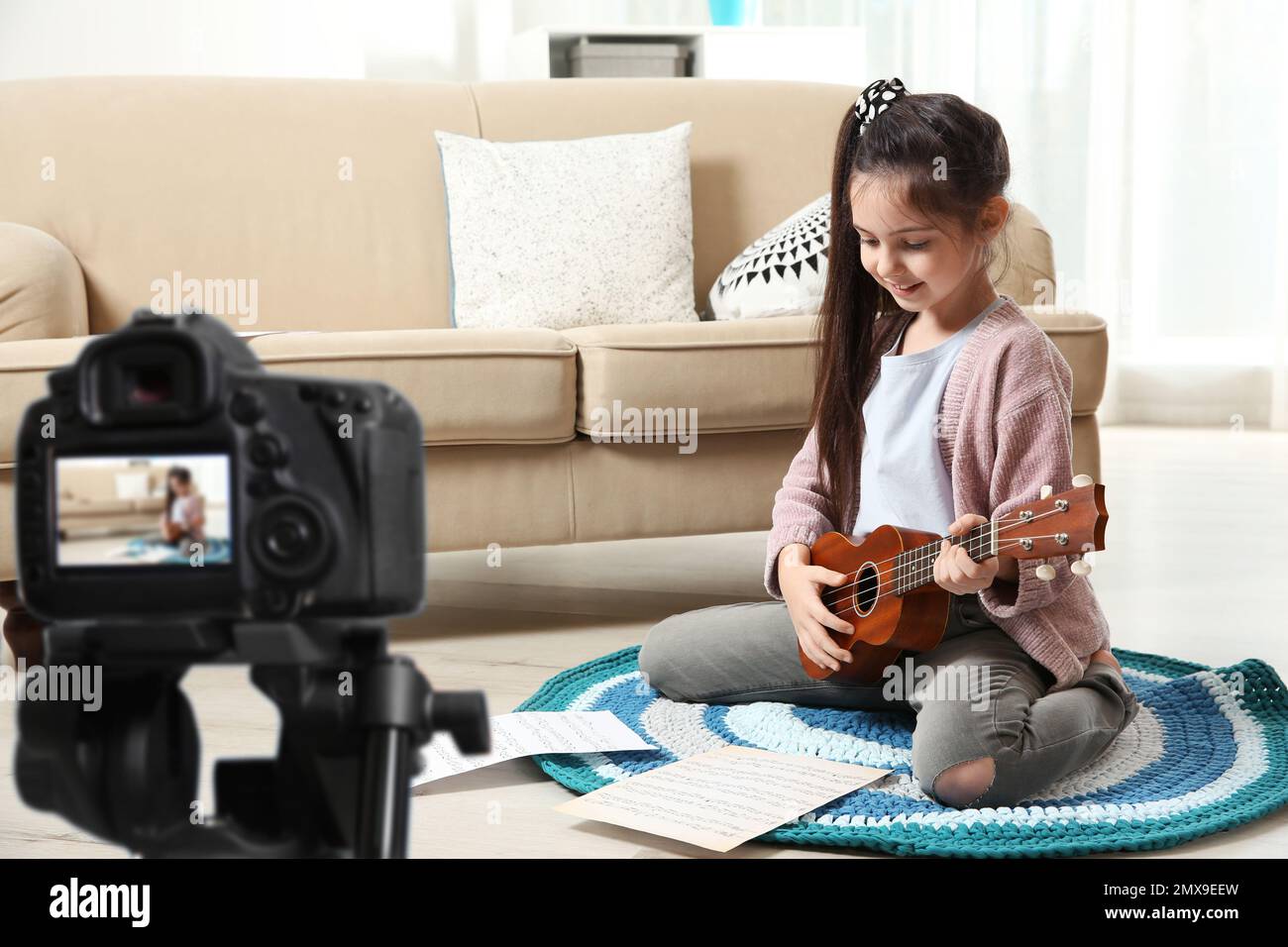 Little music teacher recording guitar lesson indoors Stock Photo - Alamy