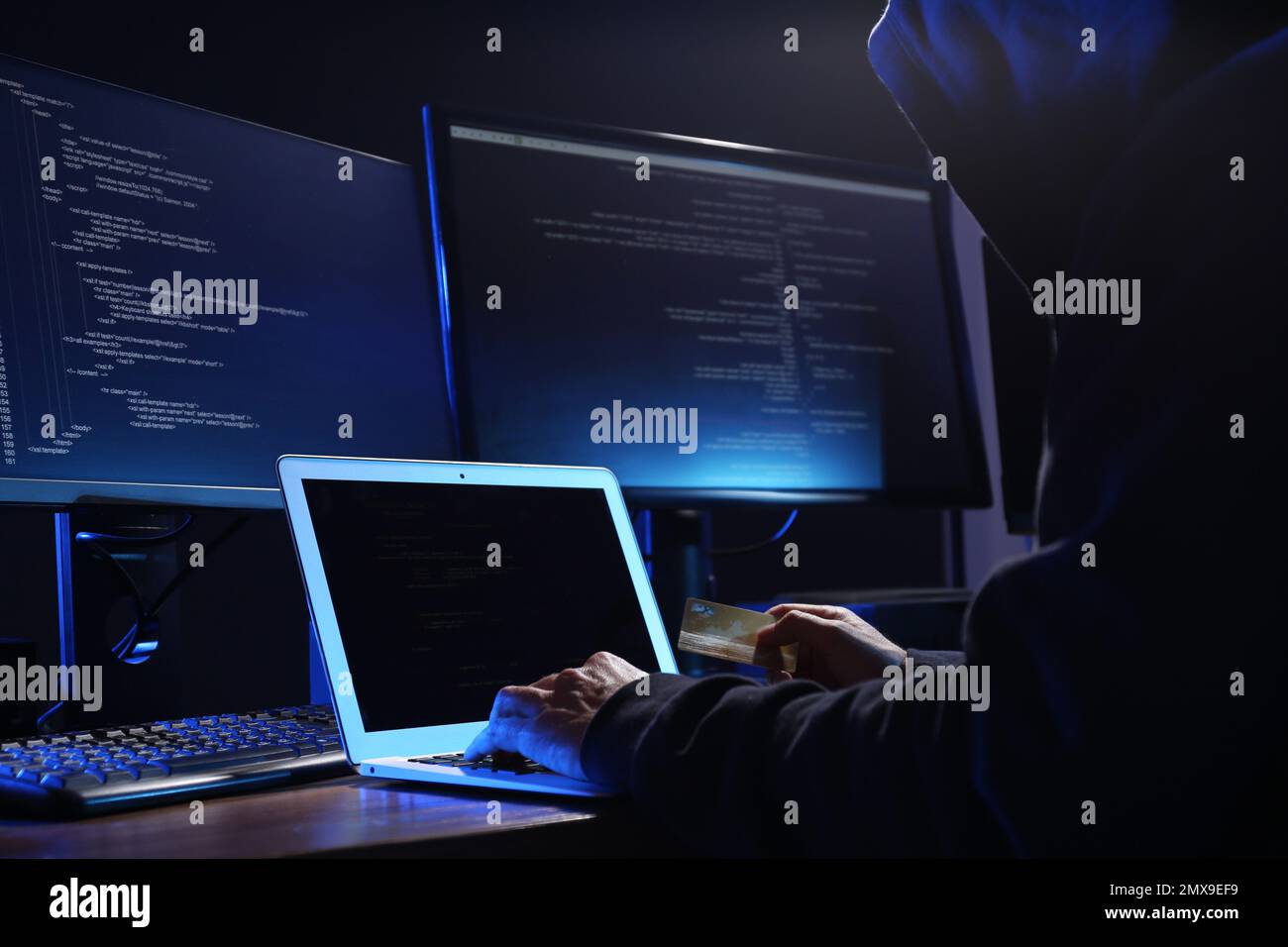 Hacker with computers and credit card in dark room, closeup. Cyber ...