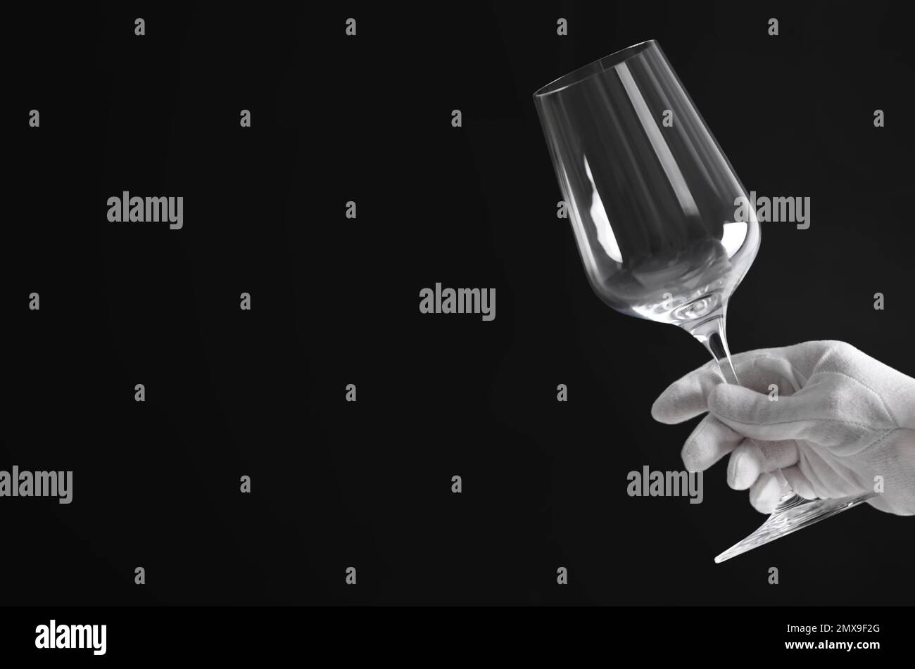 Person in white glove checking cleanliness of glass on dark background ...