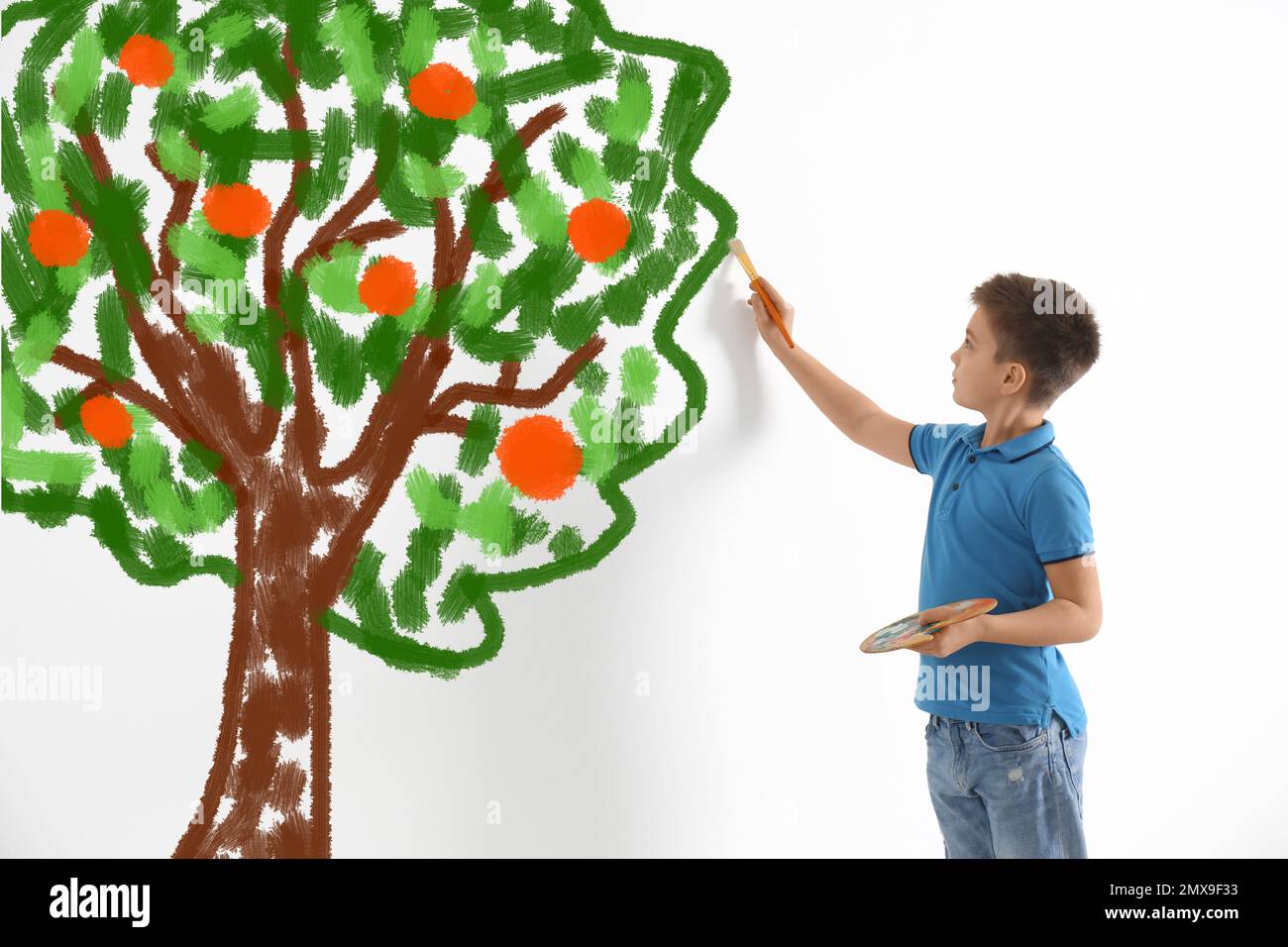 Cute child drawing tree on white wall indoors Stock Photo - Alamy