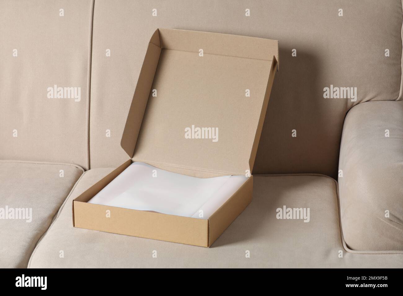 Open cardboard box on sofa at home Stock Photo - Alamy