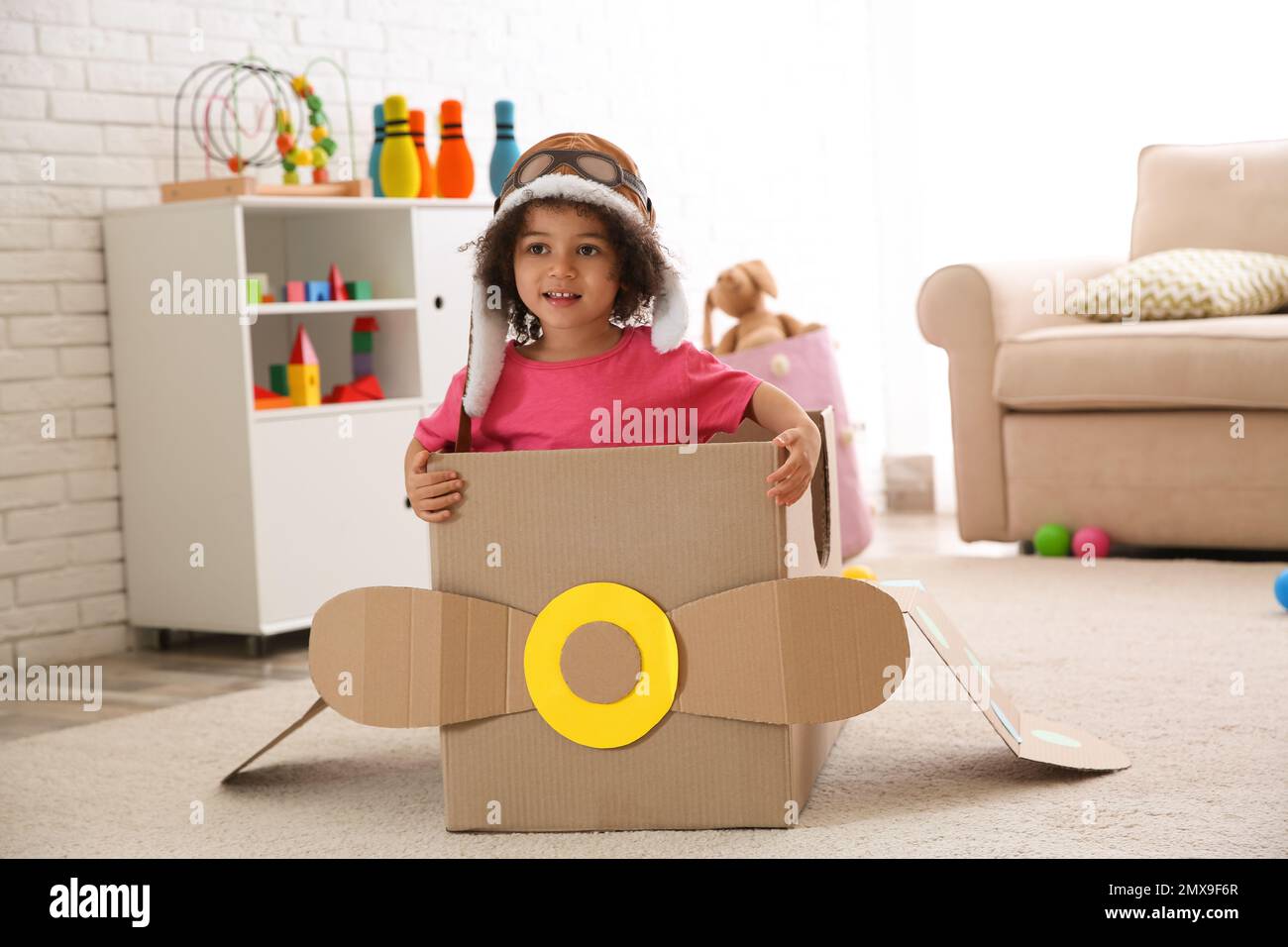 Cute African American child playing with cardboard plane at home Stock ...