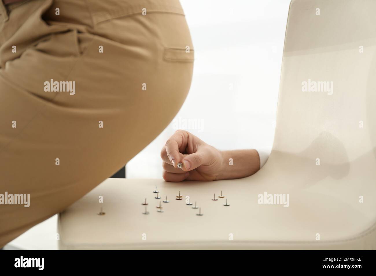 Man putting pins on chair while his colleague sitting down, closeup ...