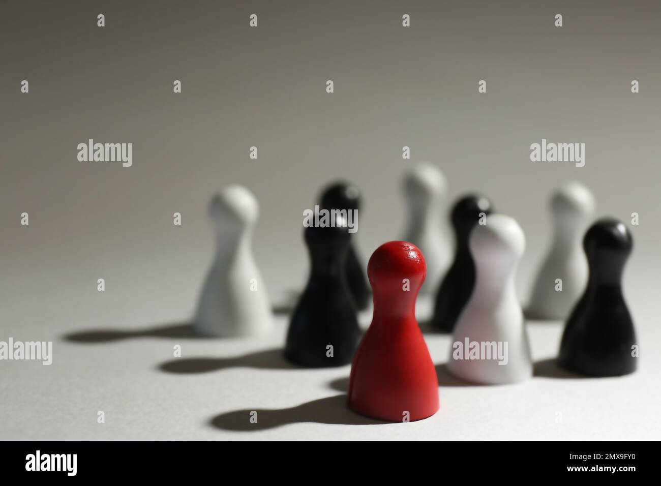 Red game piece among black and white ones on light grey background ...
