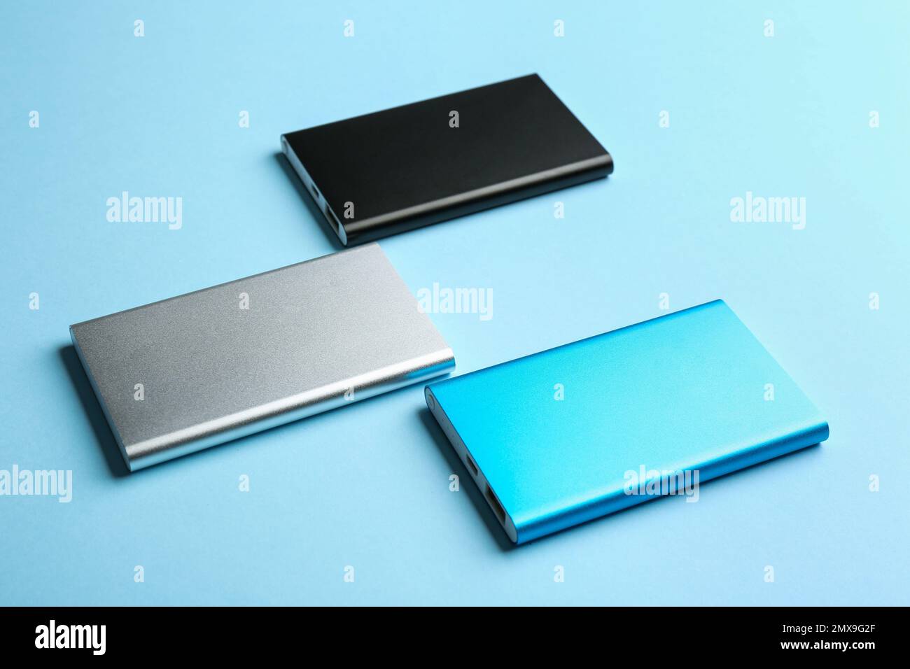 Modern external portable chargers on light blue background Stock Photo ...