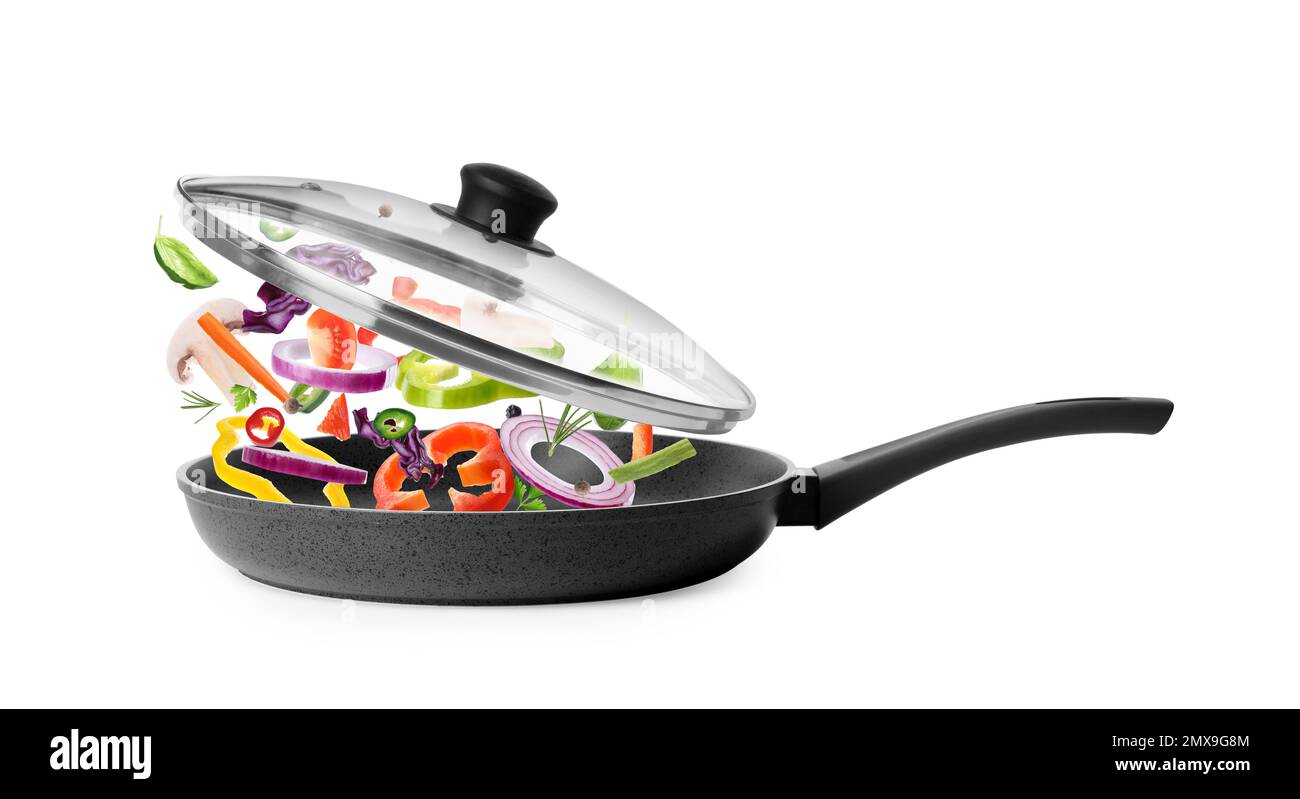Different vegetables falling into frying pan on white background ...