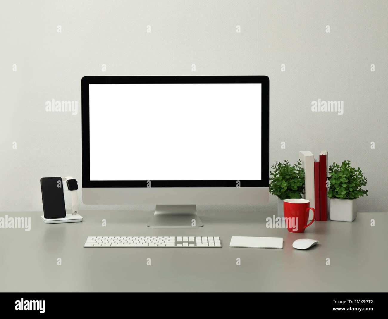 Modern workplace with computer, charging devices and houseplants ...