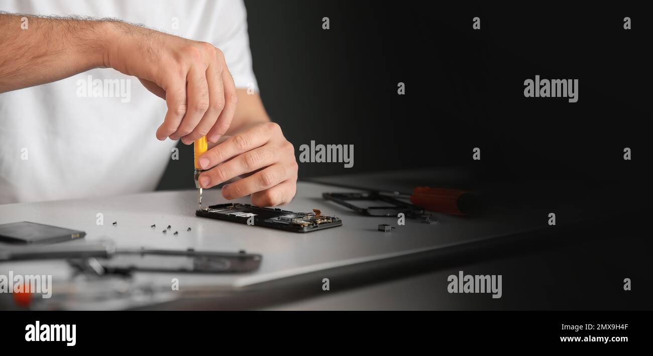 Technician repairing mobile phone at table, space for text. Banner ...