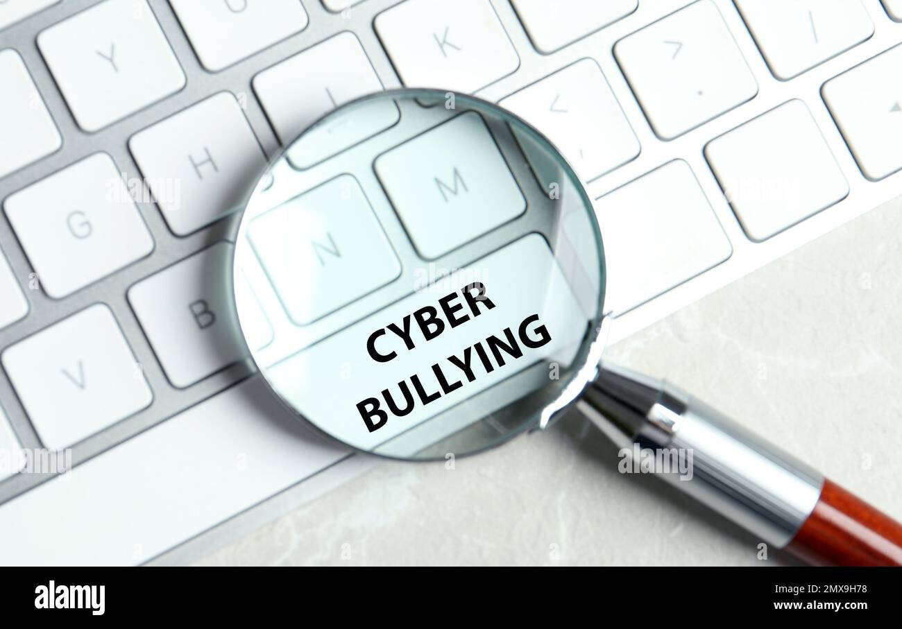 Magnifying glass and computer keyboard with phrase CYBER BULLYING on ...