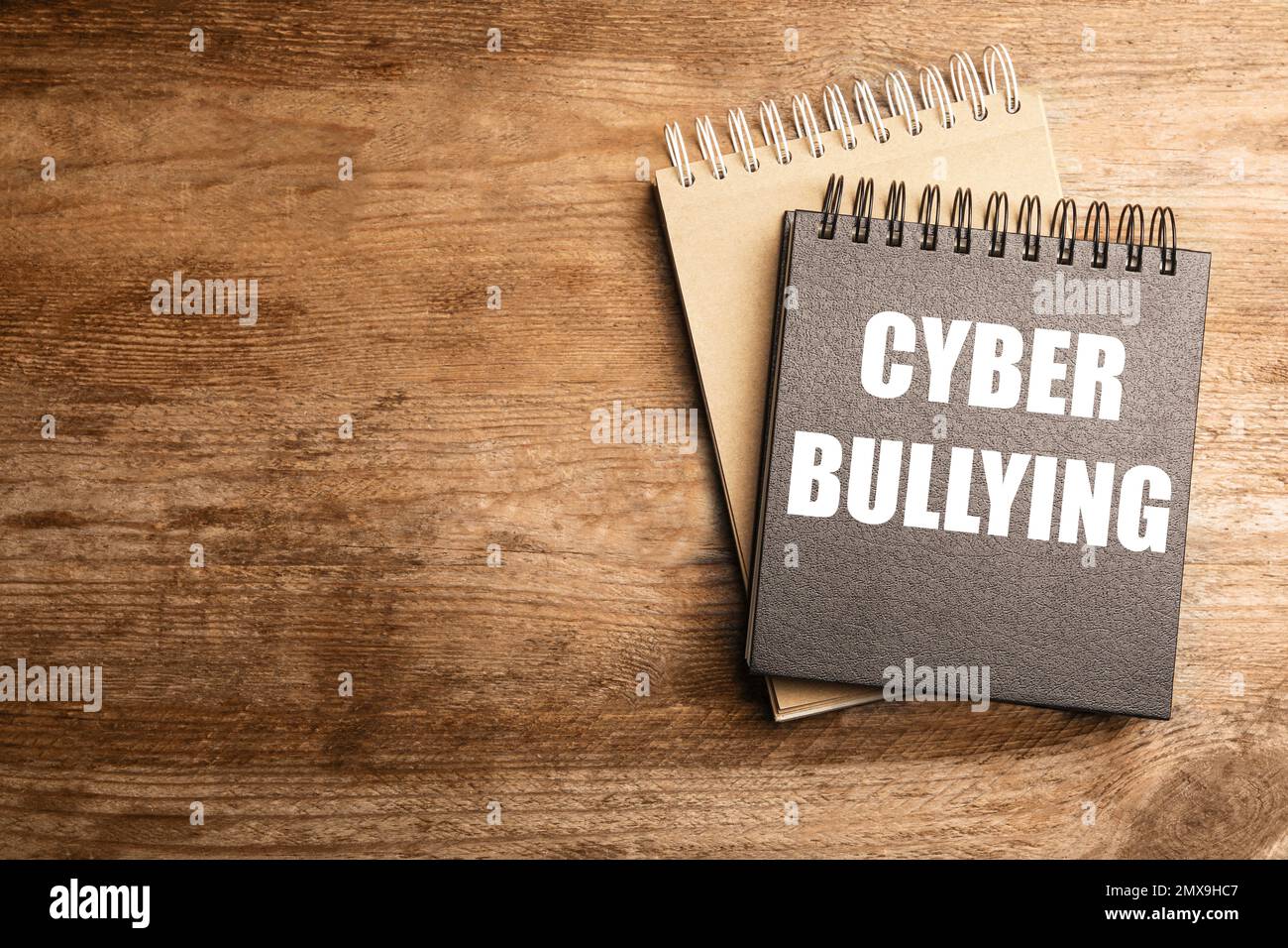 Stylish notebooks with phrase CYBER BULLYING on wooden table, top view ...