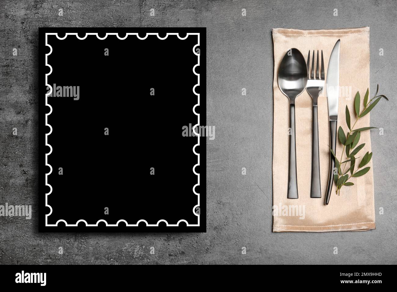 Cutlery and empty menu on gray background, top view. Space for text ...