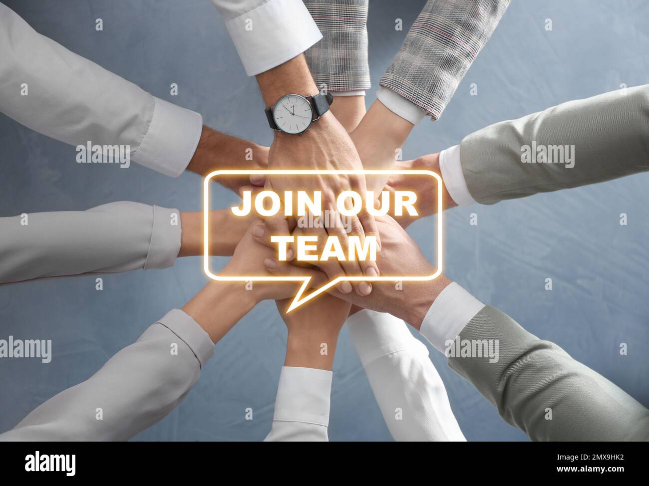 People holding hands together over grey stone background, closeup. Join ...