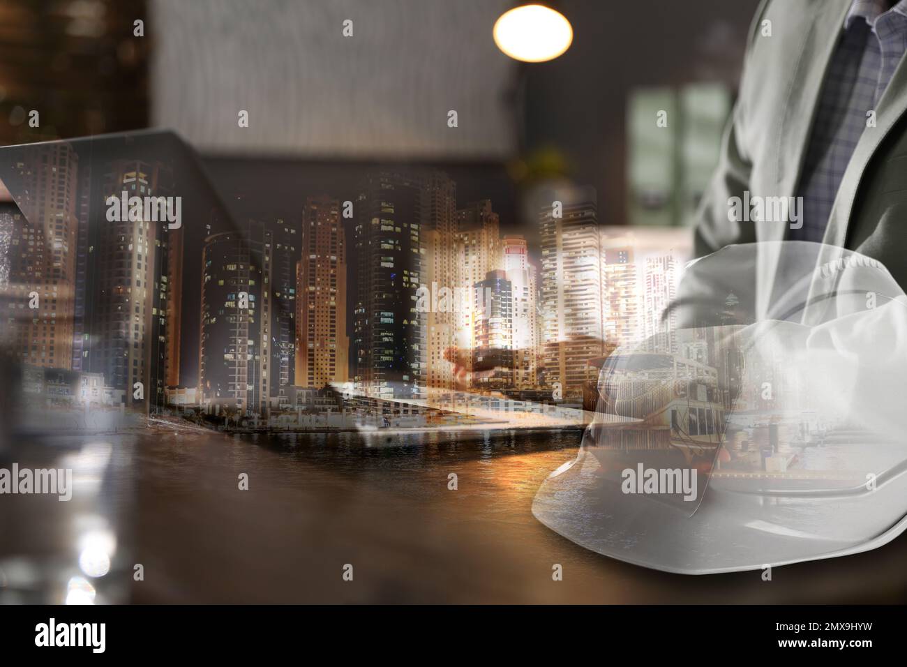 Engineer with laptop at table in office and night cityscape, closeup ...