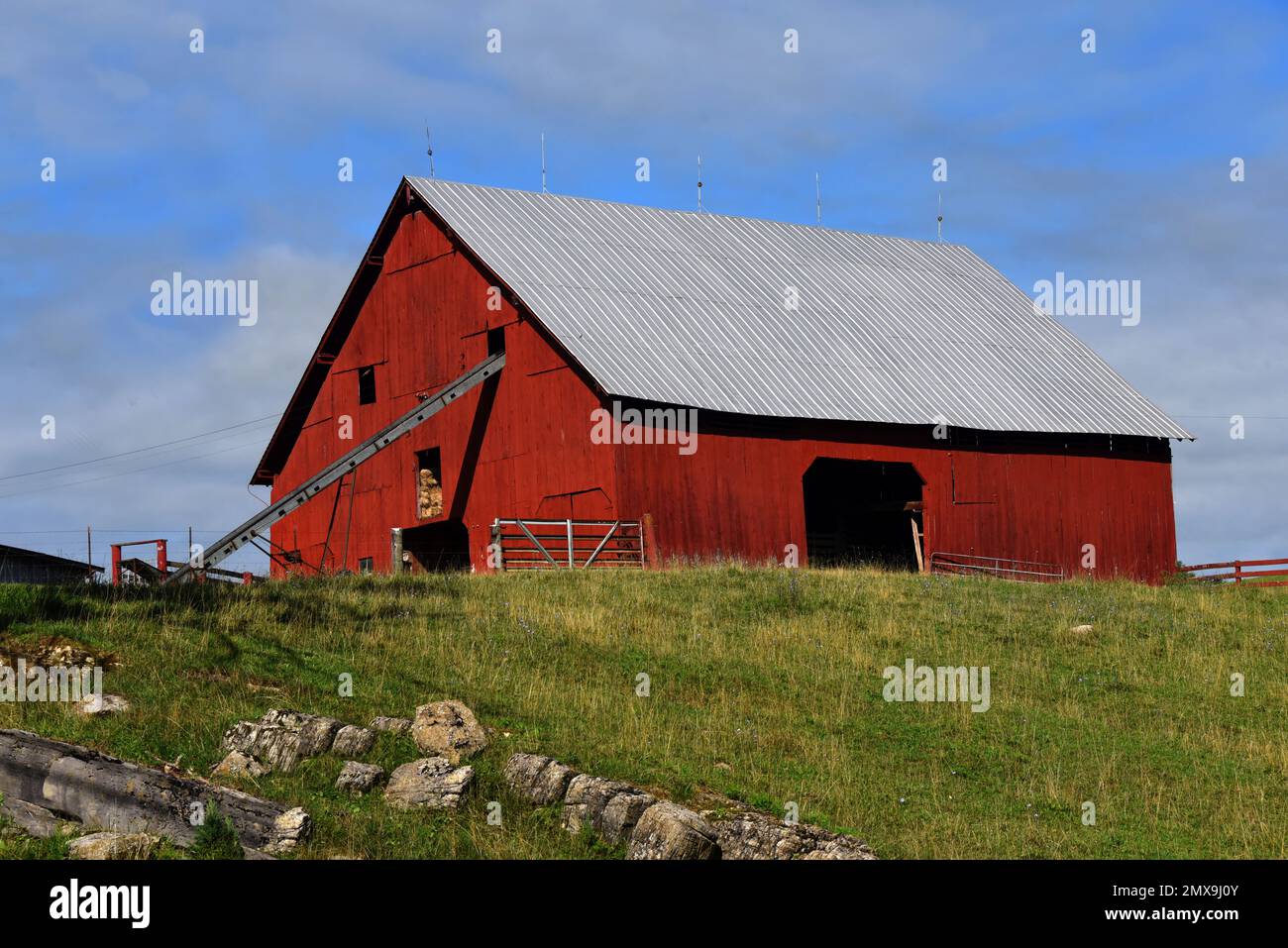 Hay elevator sits inside loft window on a rustic, red, wooden barn in ...
