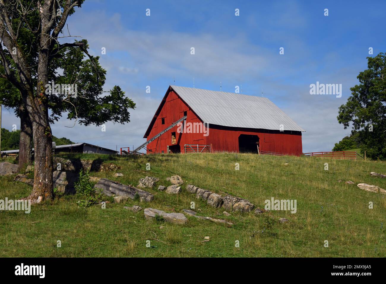 Hay elevator extends into loft window. Barn is red, wooden and has tin ...