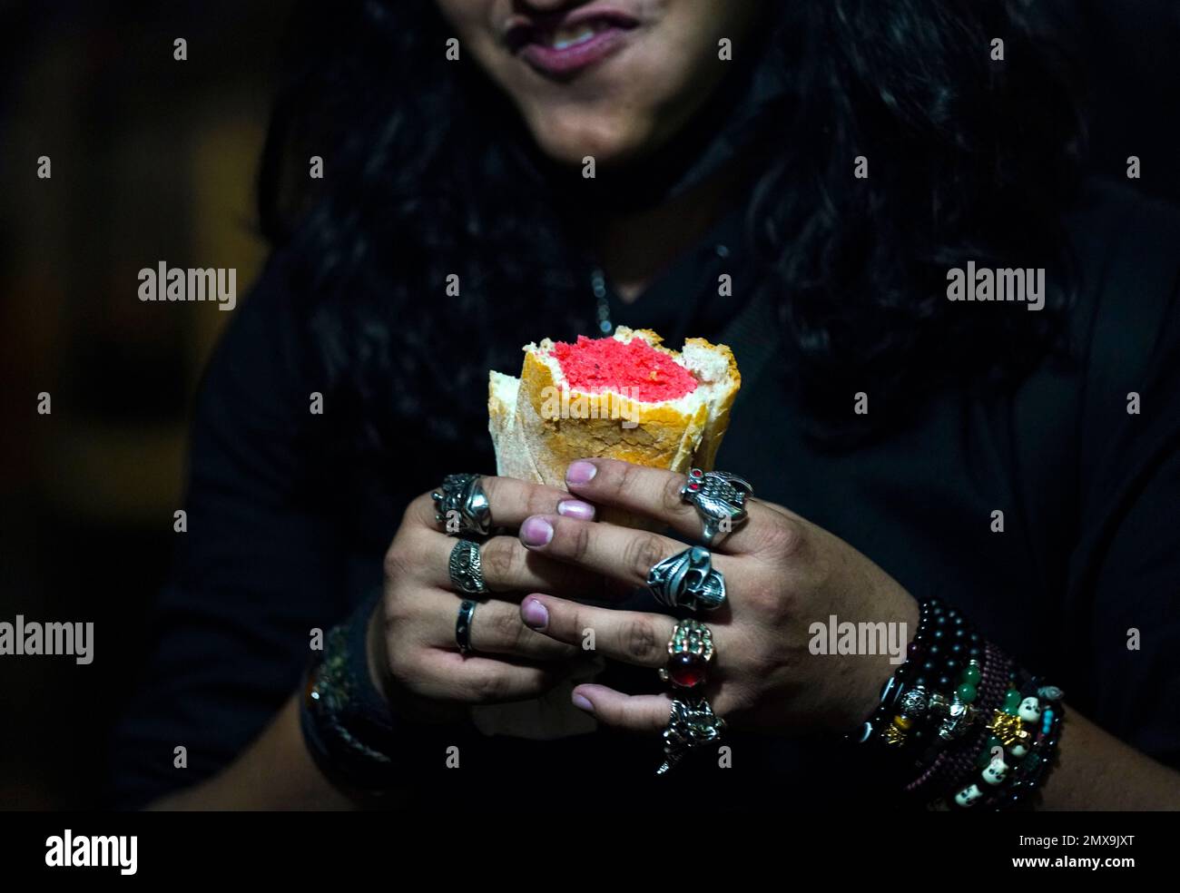 A rock musician eats a sweet masa tamal inside a crusty bun at a street ...