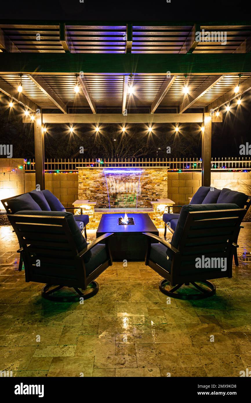 A resort style backyard at night with a waterfall, pergola, and a ...