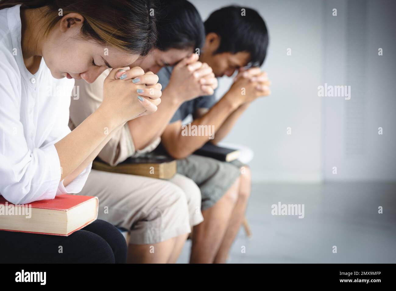 A group of Asian Christians sits inside a Catholic Church praying for ...