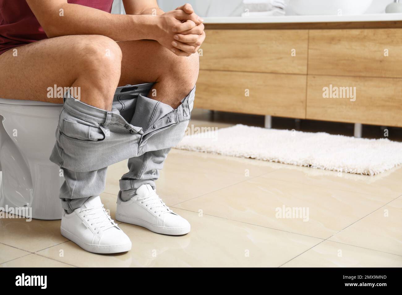 Man sitting on toilet bowl in bathroom, closeup Stock Photo - Alamy