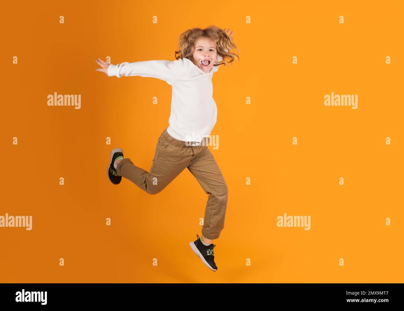 Full length of excited kid jumping. Little child jumping over a yellow ...