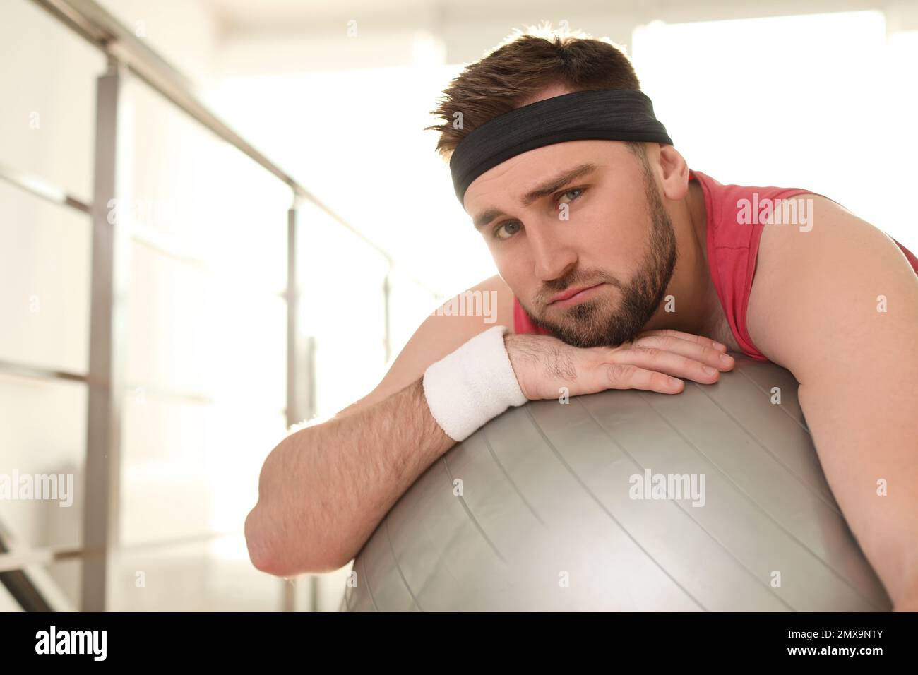 Lazy young man with exercise ball indoors Stock Photo - Alamy