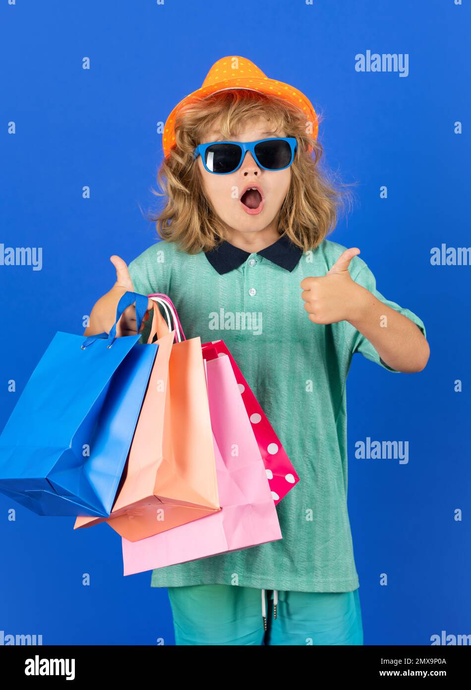 Child in fashion clothes goes shopping. Kid with shopping packages ...