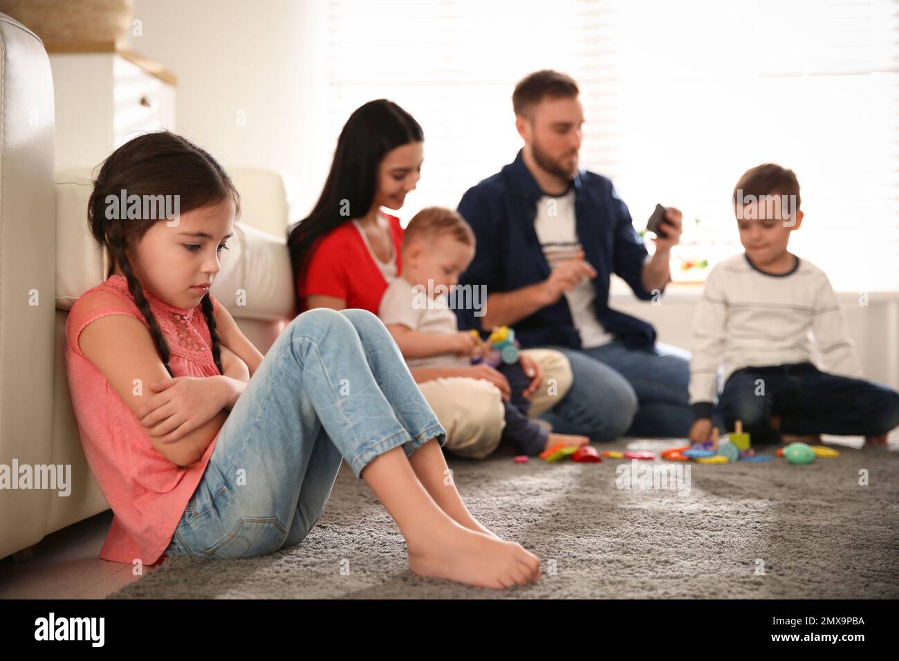 Unhappy little girl feeling jealous while parents spending time with ...